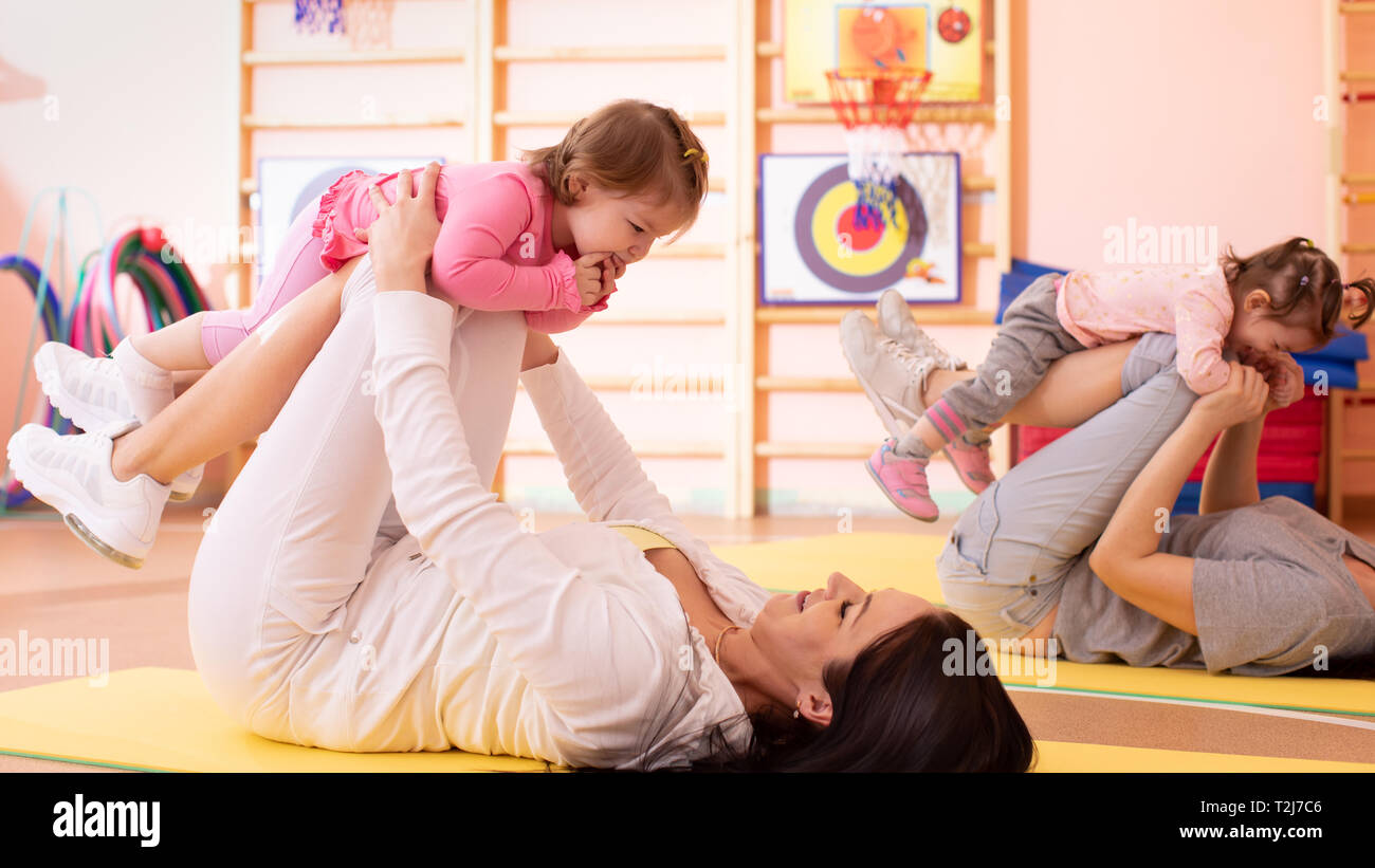 Babies have fun pastime while mothers doing workout in gym class to ...