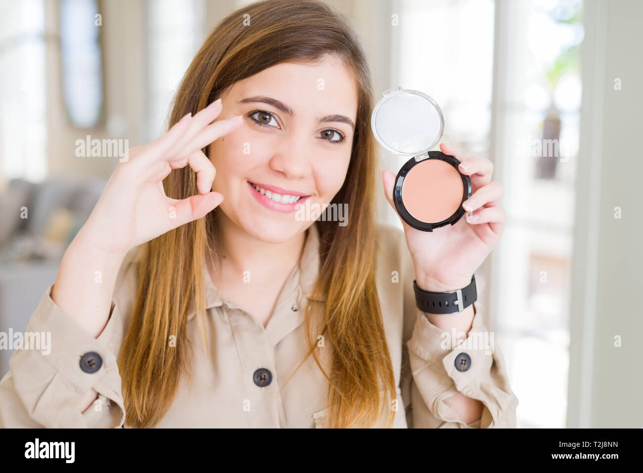 Beautiful young woman using make up cosmetics applying powder doing ok ...