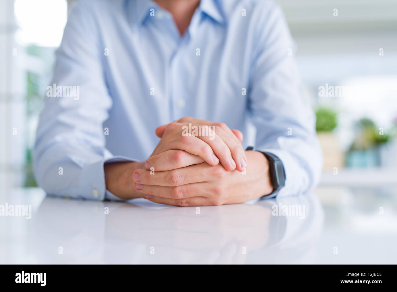 Close up of man crossed hands over white table Stock Photo - Alamy