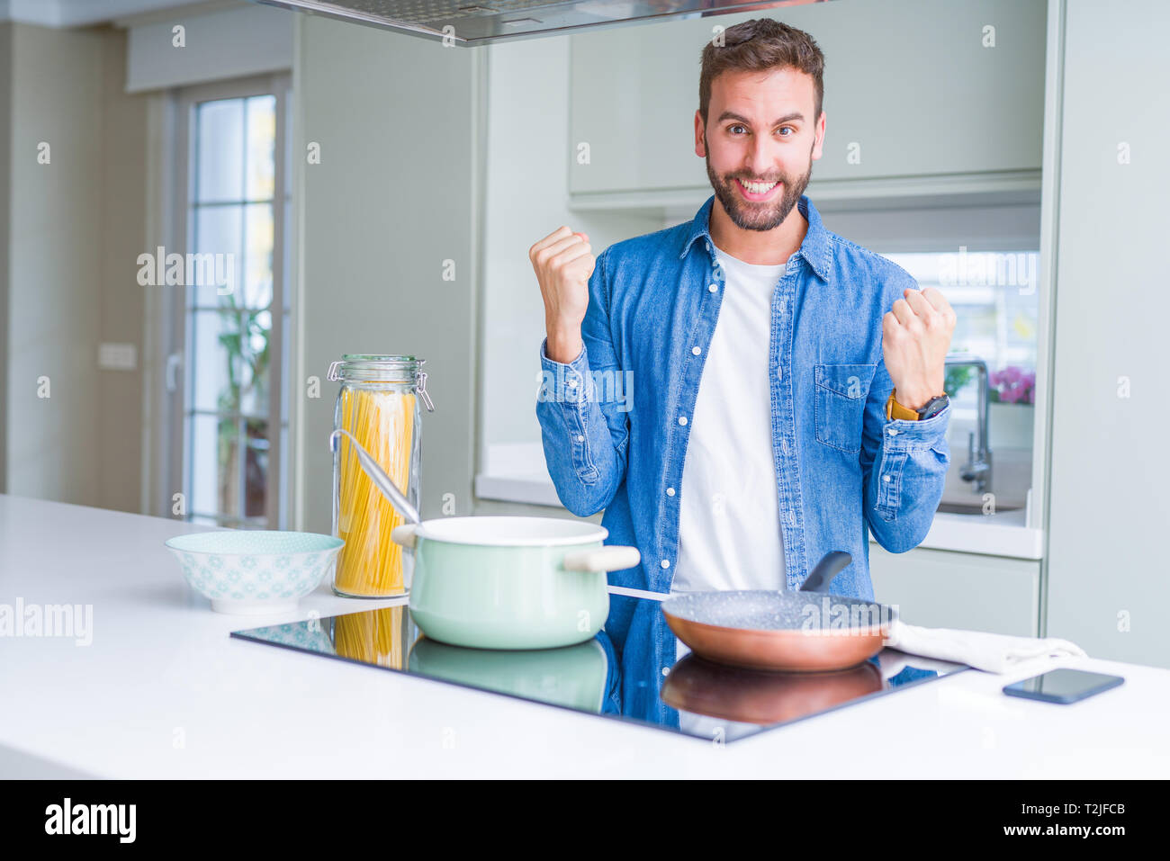 Handsome man cooking italian spaghetti pasta at the kitchen celebrating ...