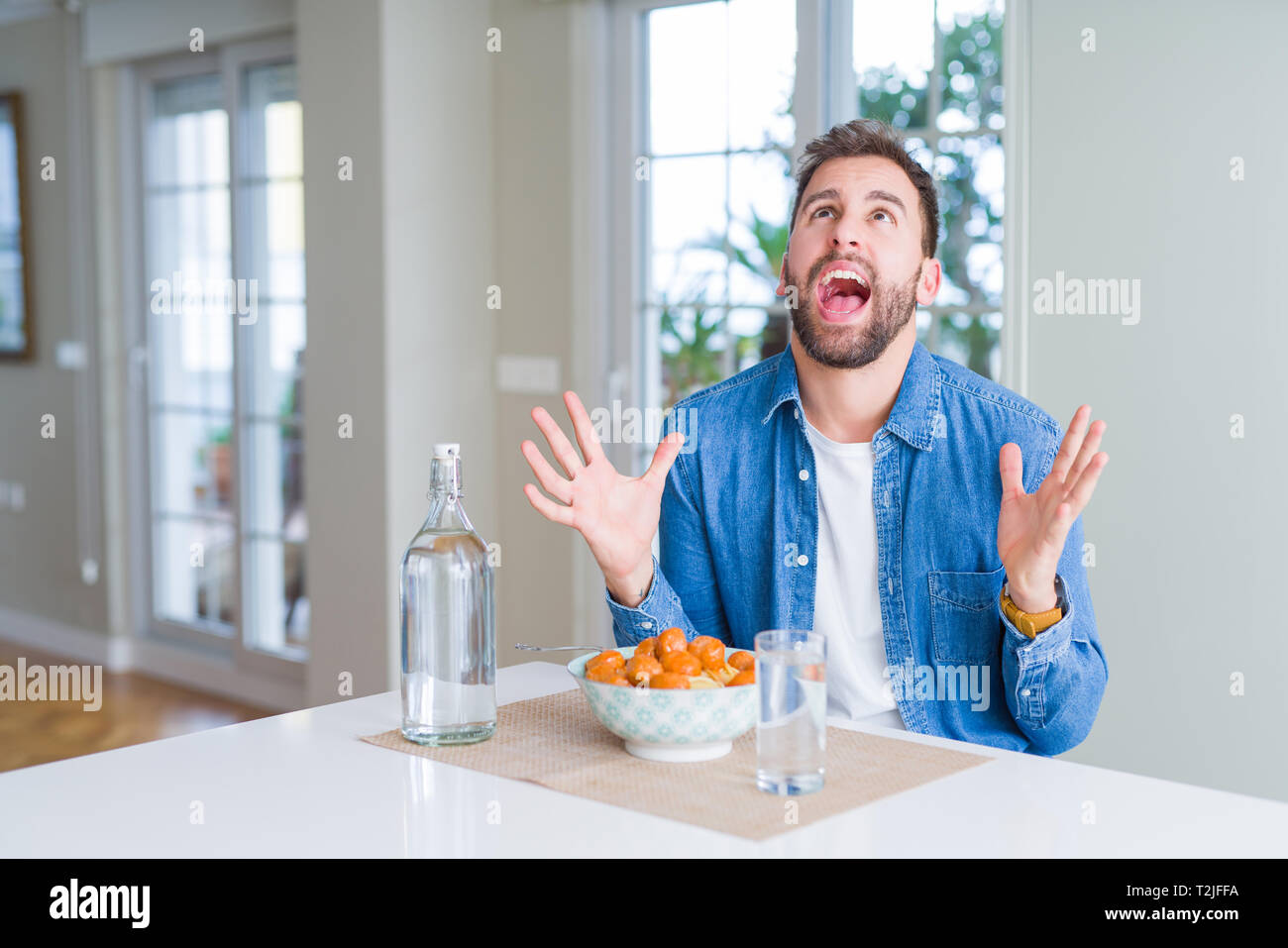 Handsome man eating pasta with meatballs and tomato sauce at home crazy ...