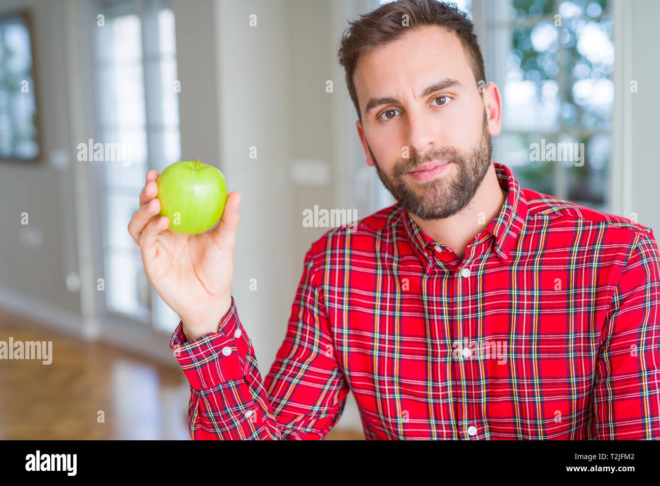 Handsome man eating fresh healthy green apple with a confident ...