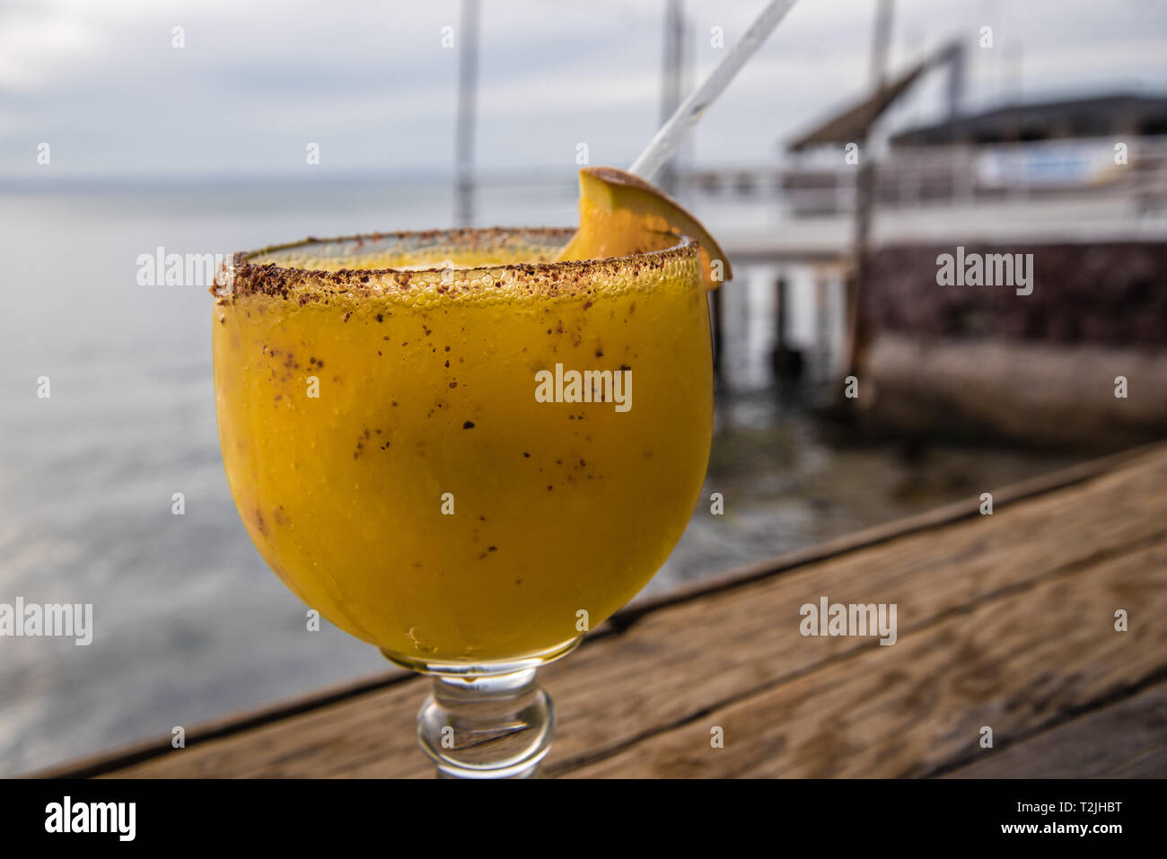 Tropical mango Cocktail by the water with an orange slaice and chili ...