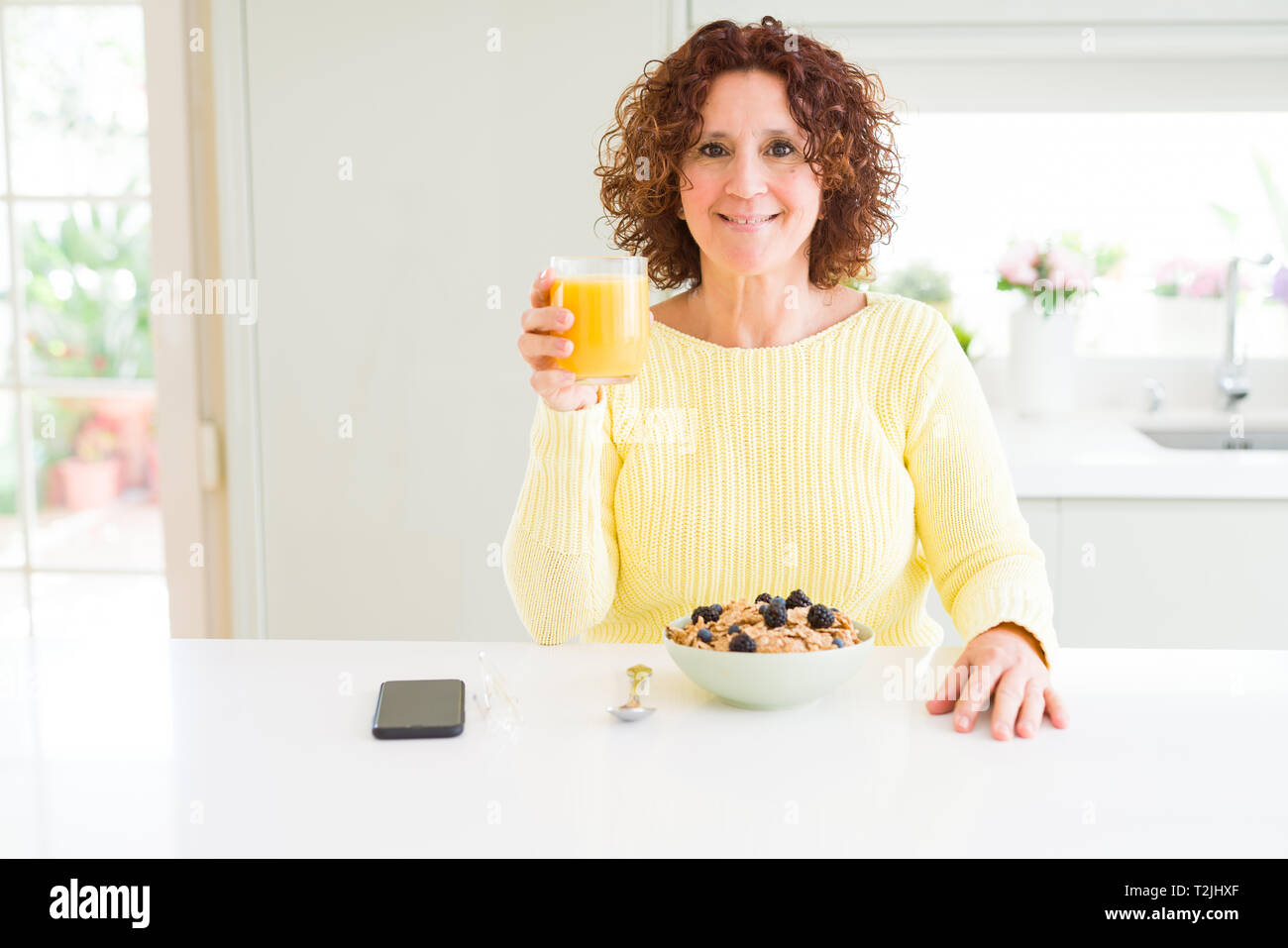 Senior woman eating healthy breakfast in the morning at home with a ...