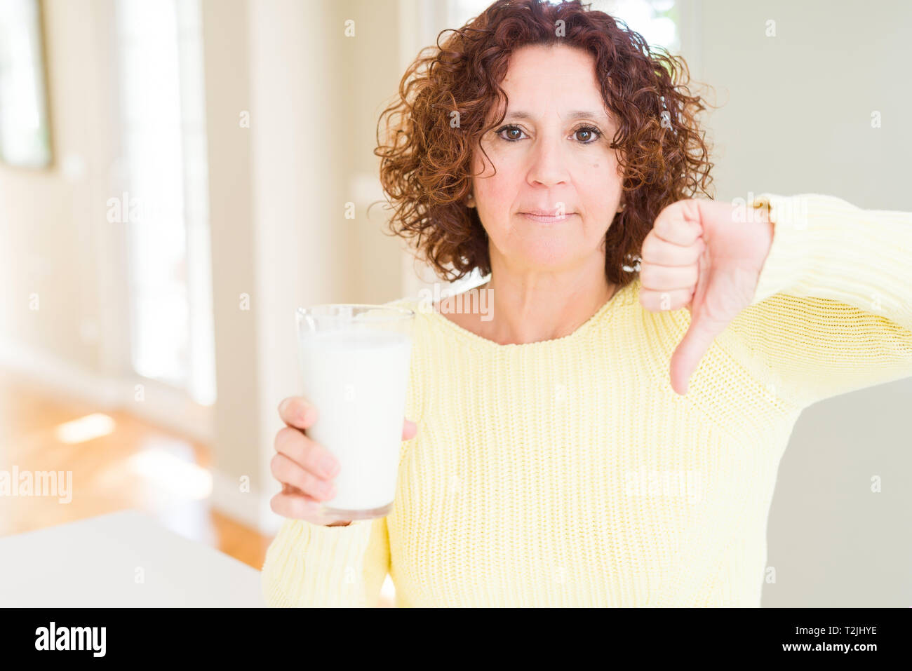 Senior woman drinking a glass of fresh milk with angry face, negative ...