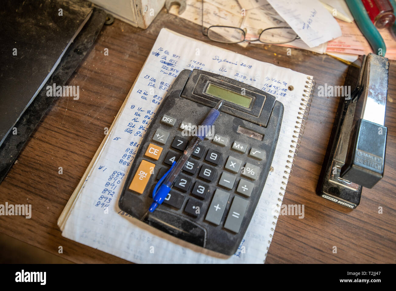 Well used calculator rests on top of lined notebook on desk ...