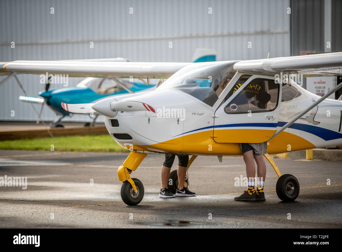 Side view of two people inspect cockpit of Tecnam P92 Eaglet airplane ...