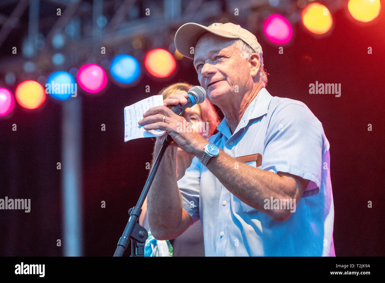 Jim Perdue speaking at microphone on stage at National Folk Festival in ...