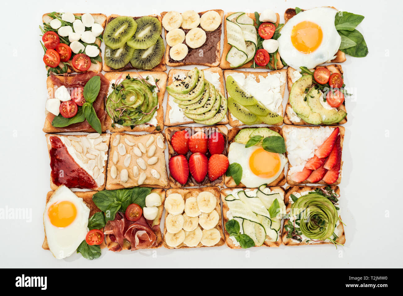 Top view of toasts with cut fruits, vegetables and peanuts on white ...