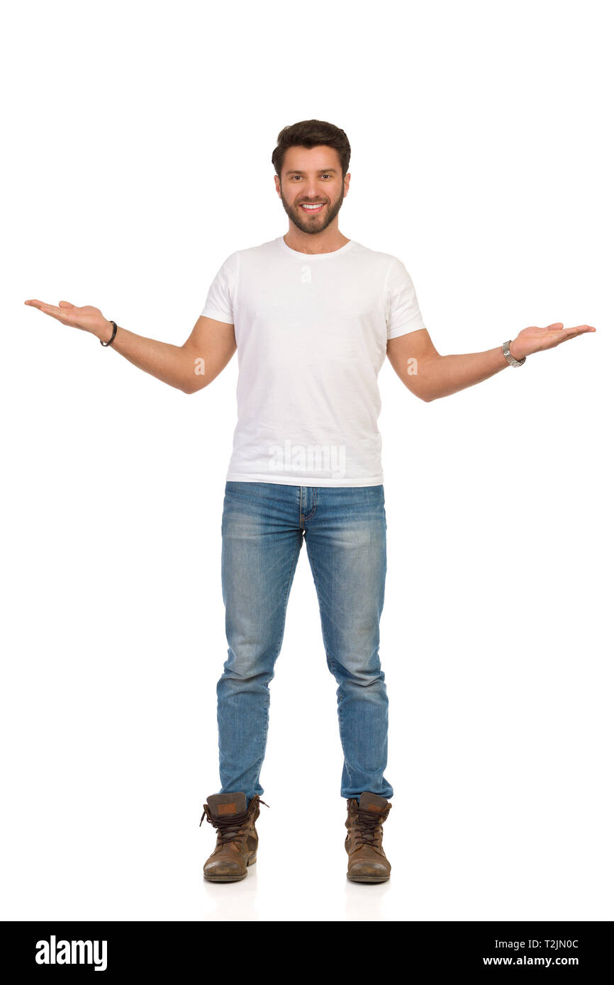 Young man in jeans and white t-shirt is standing with arms outstretched ...