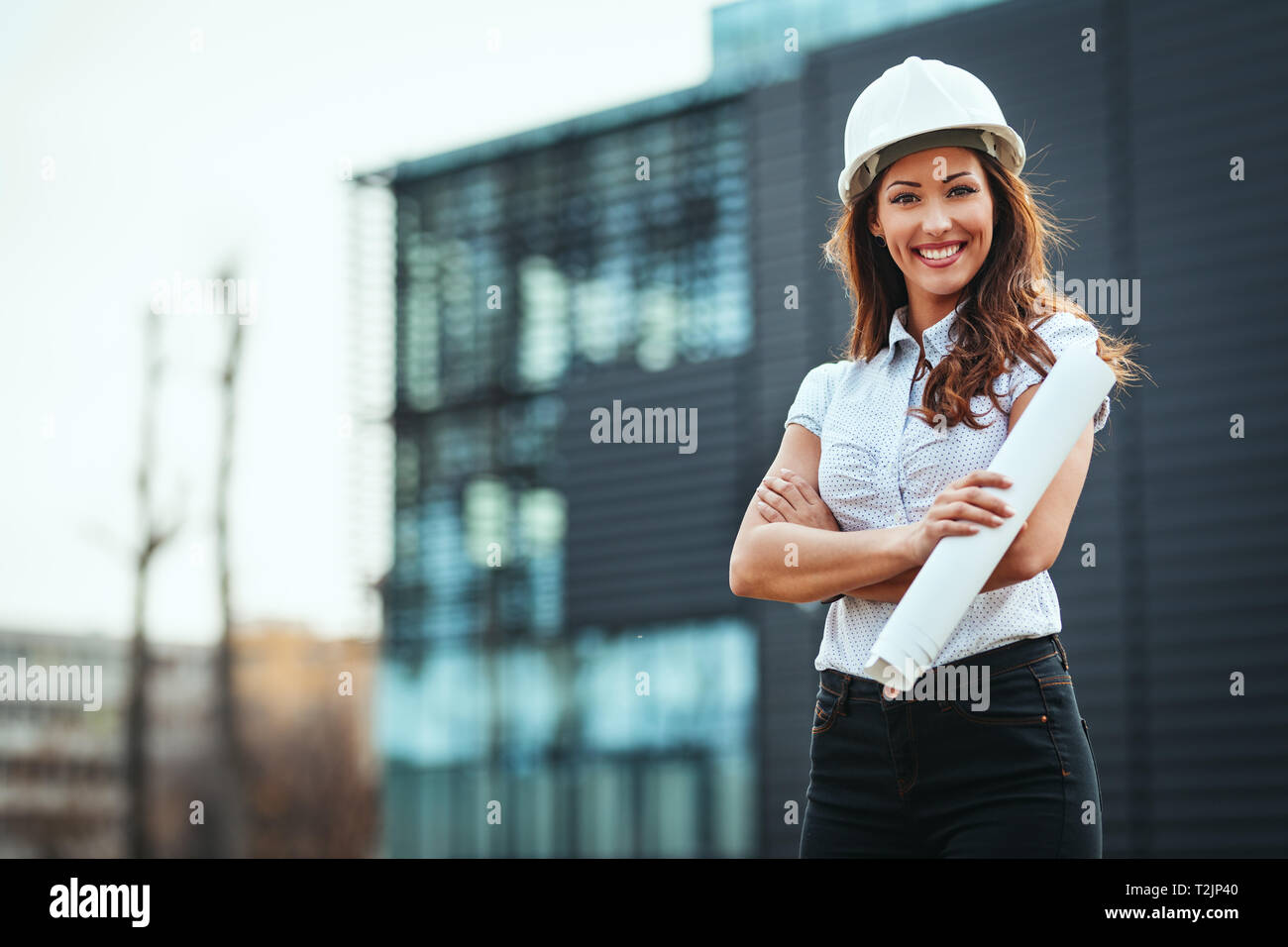 Young successful female engineer with white helmet and blueprints in ...