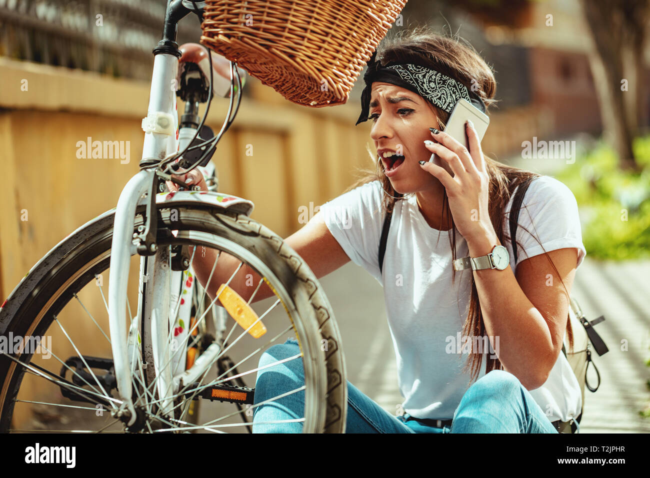 Outdoor shot of young woman who is squatting beside the bike, on a city ...