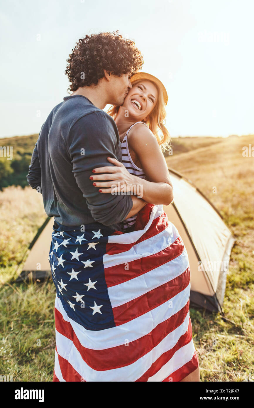 Happy young couple enjoys a sunny day in nature. They're hugging each ...
