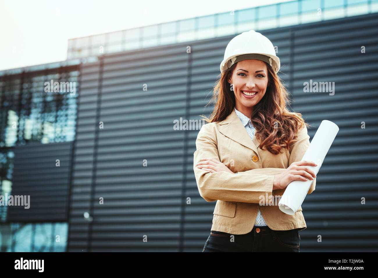 Young successful female engineer with white helmet and blueprints in ...