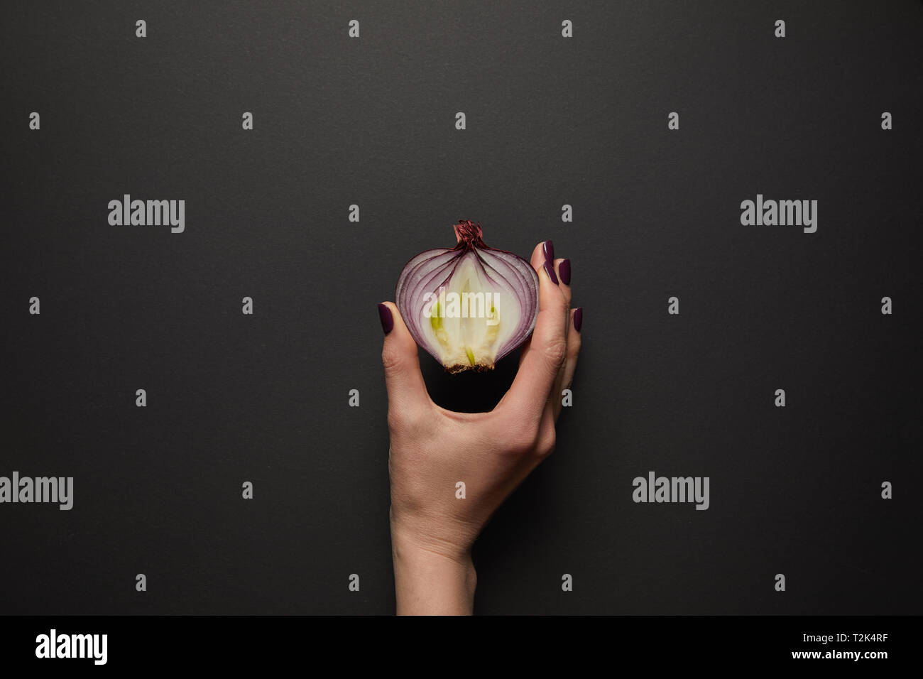 Partial view of woman holding cut onion on black surface Stock Photo ...
