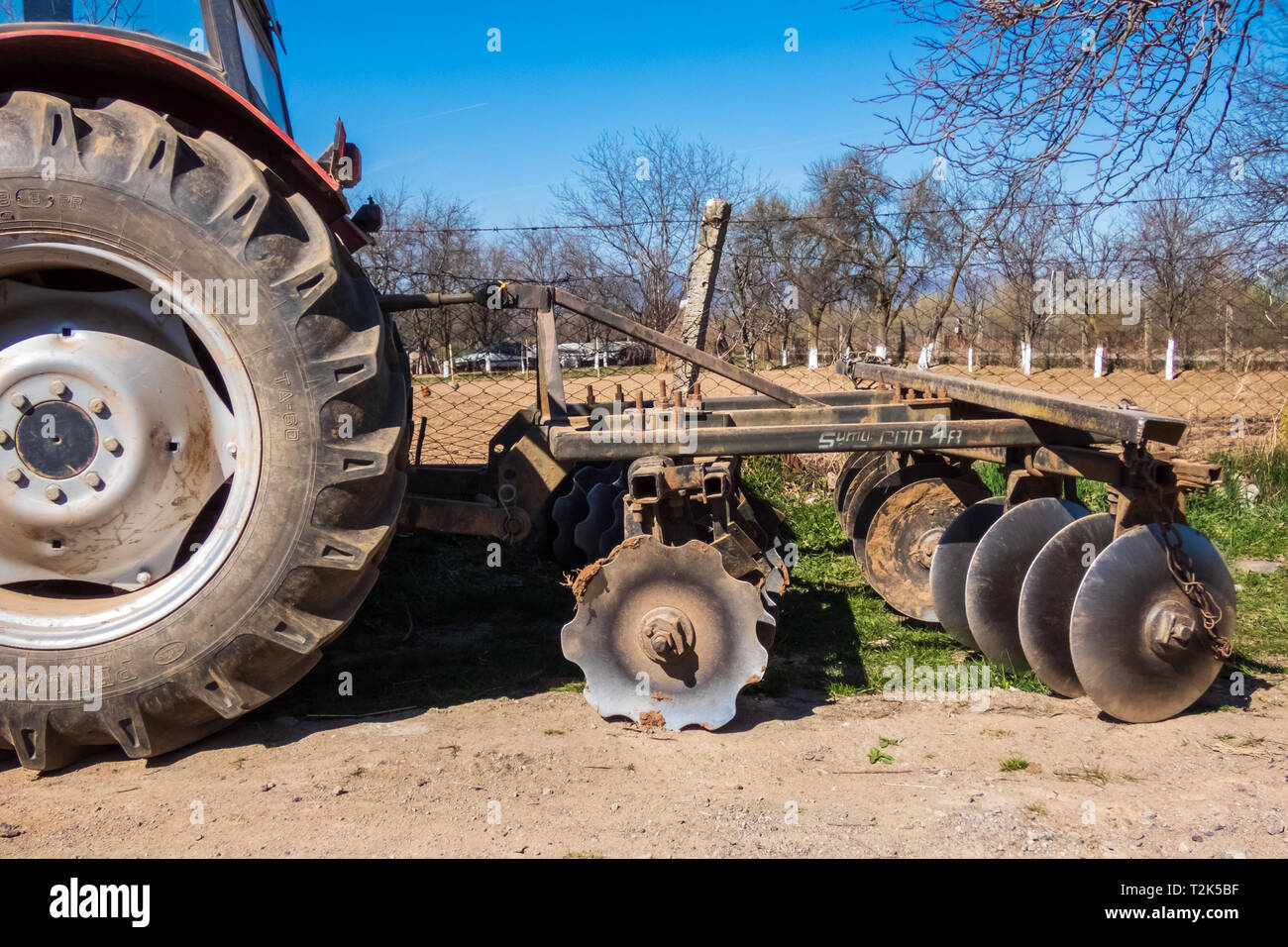 Agricultural plough connected to a big old tractor Stock Photo - Alamy