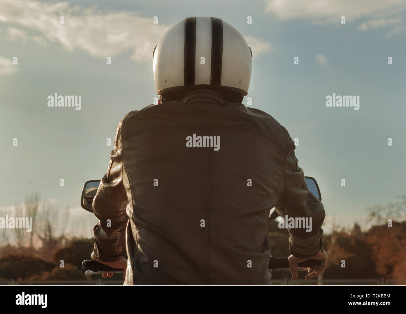 Man riding motorbike with brown leather jacket and helmet seen from ...