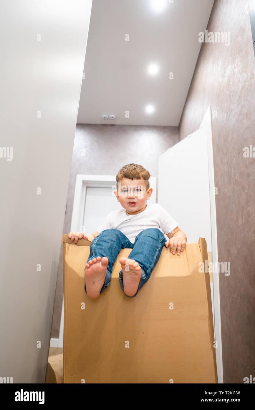 Cute little boy sitting on a cardboard box in the corridor Stock Photo ...