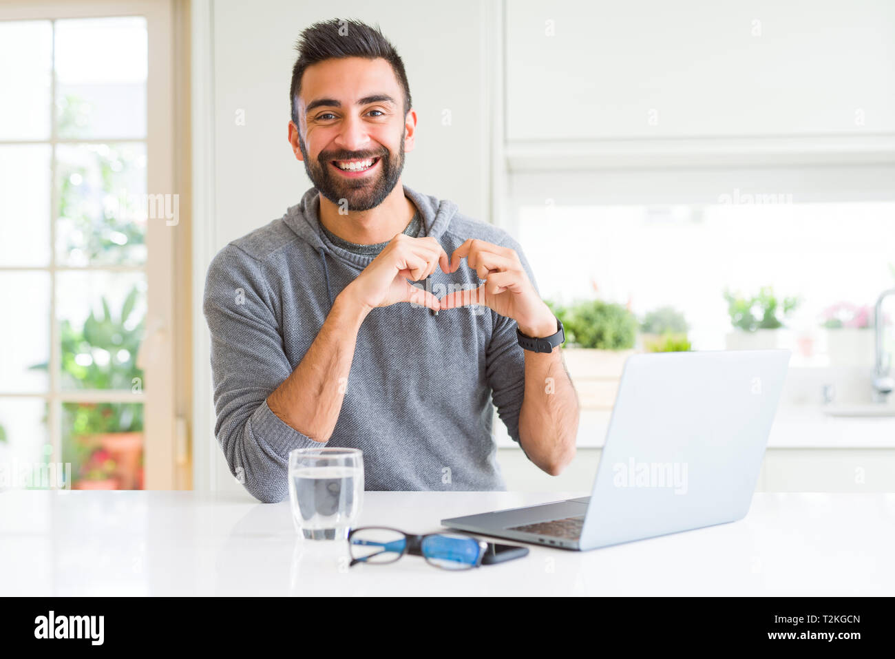 Handsome hispanic man working using computer laptop smiling in love ...