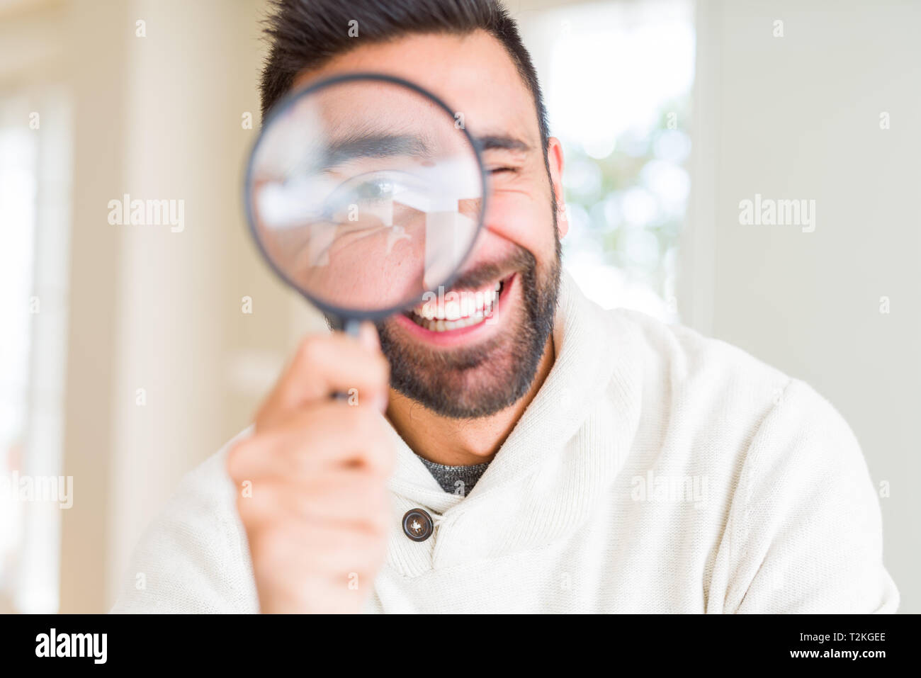 Handsome man using magnifying glass, doing funny faces Stock Photo - Alamy