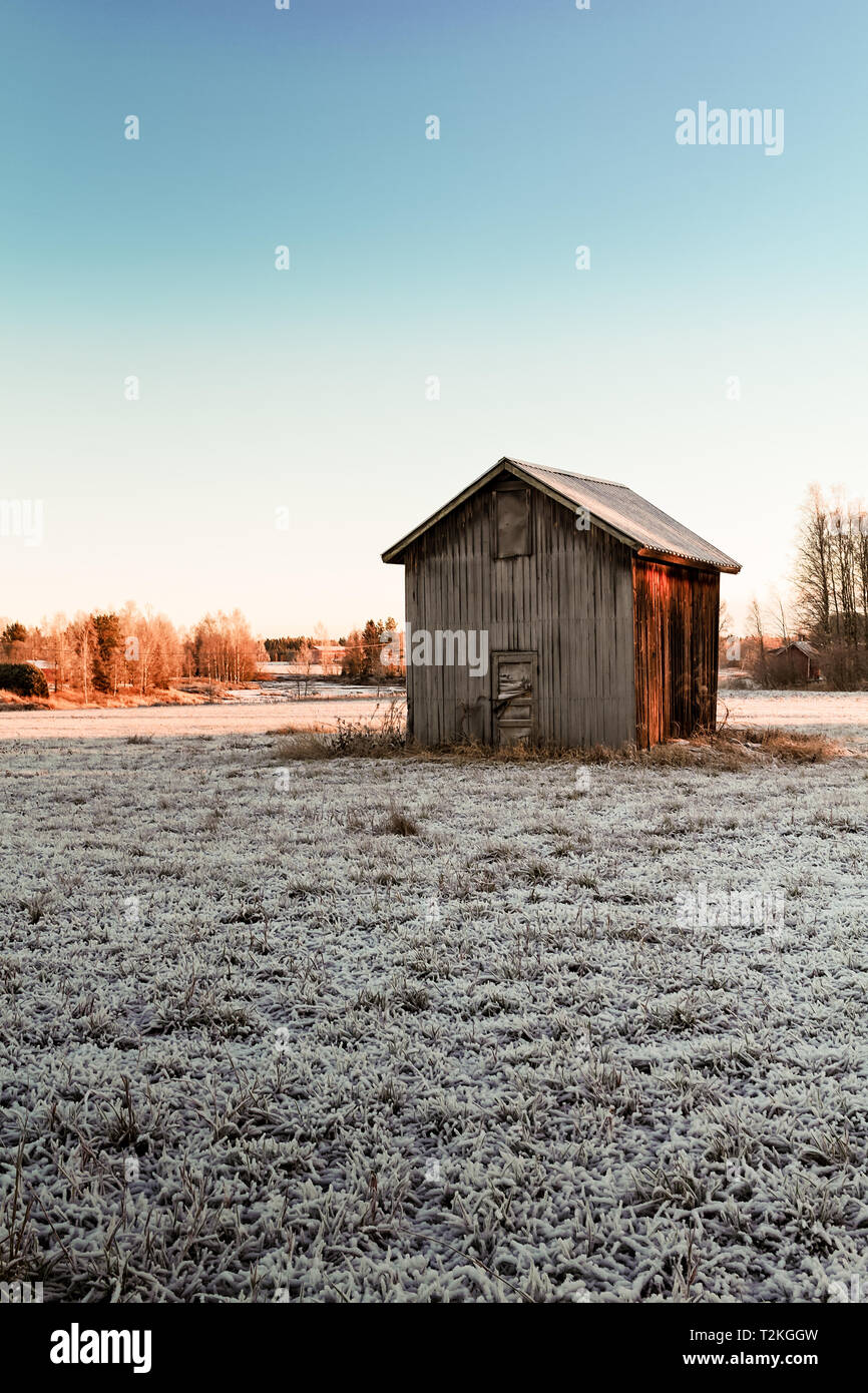 A tiny barn house stands on the frosty fields of the Northern Finland ...