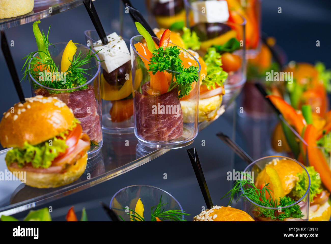 Mini canapes in plastic cups on a dark background of granite stone ...