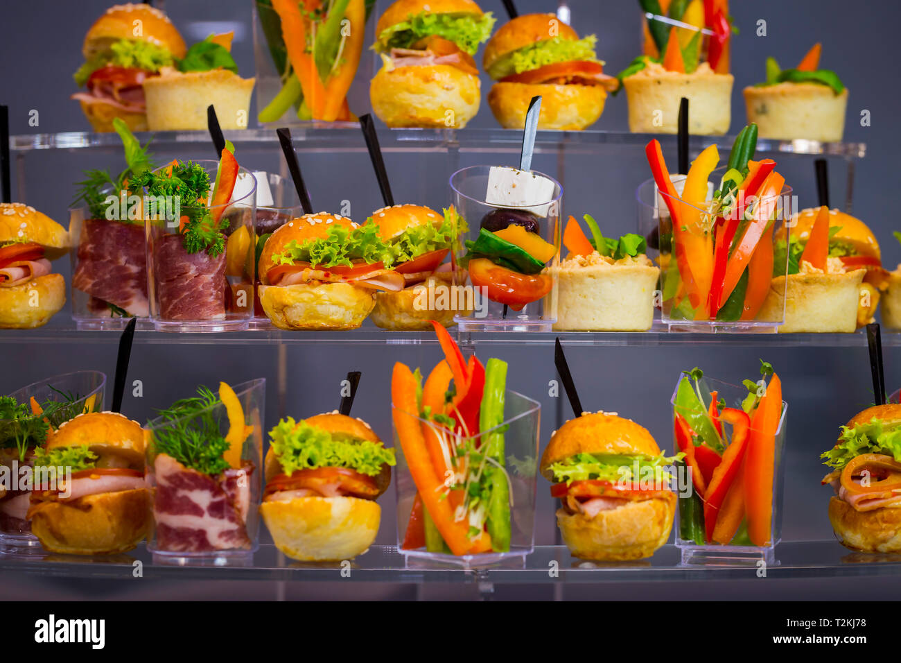 Mini canapes in plastic cups on a dark background of granite stone ...