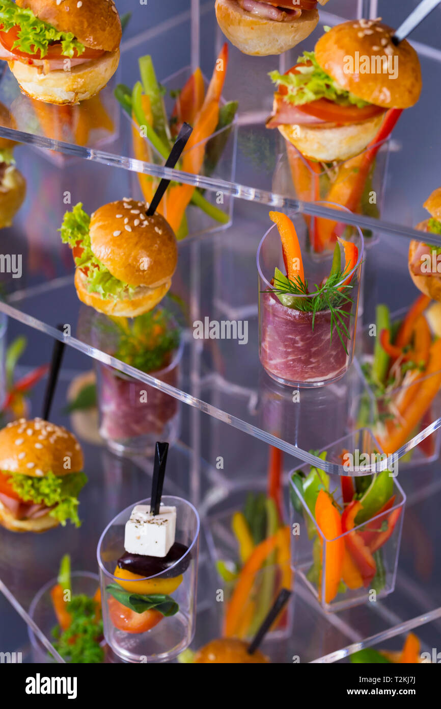 Mini canapes in plastic cups on a dark background of granite stone ...