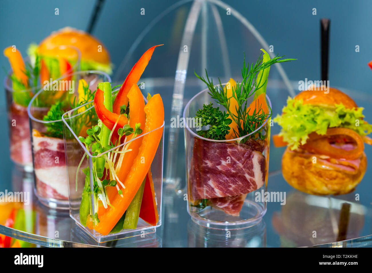 Mini canapes in plastic cups on a dark background of granite stone ...