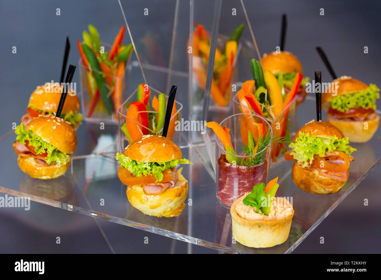 Mini canapes in plastic cups on a dark background of granite stone ...