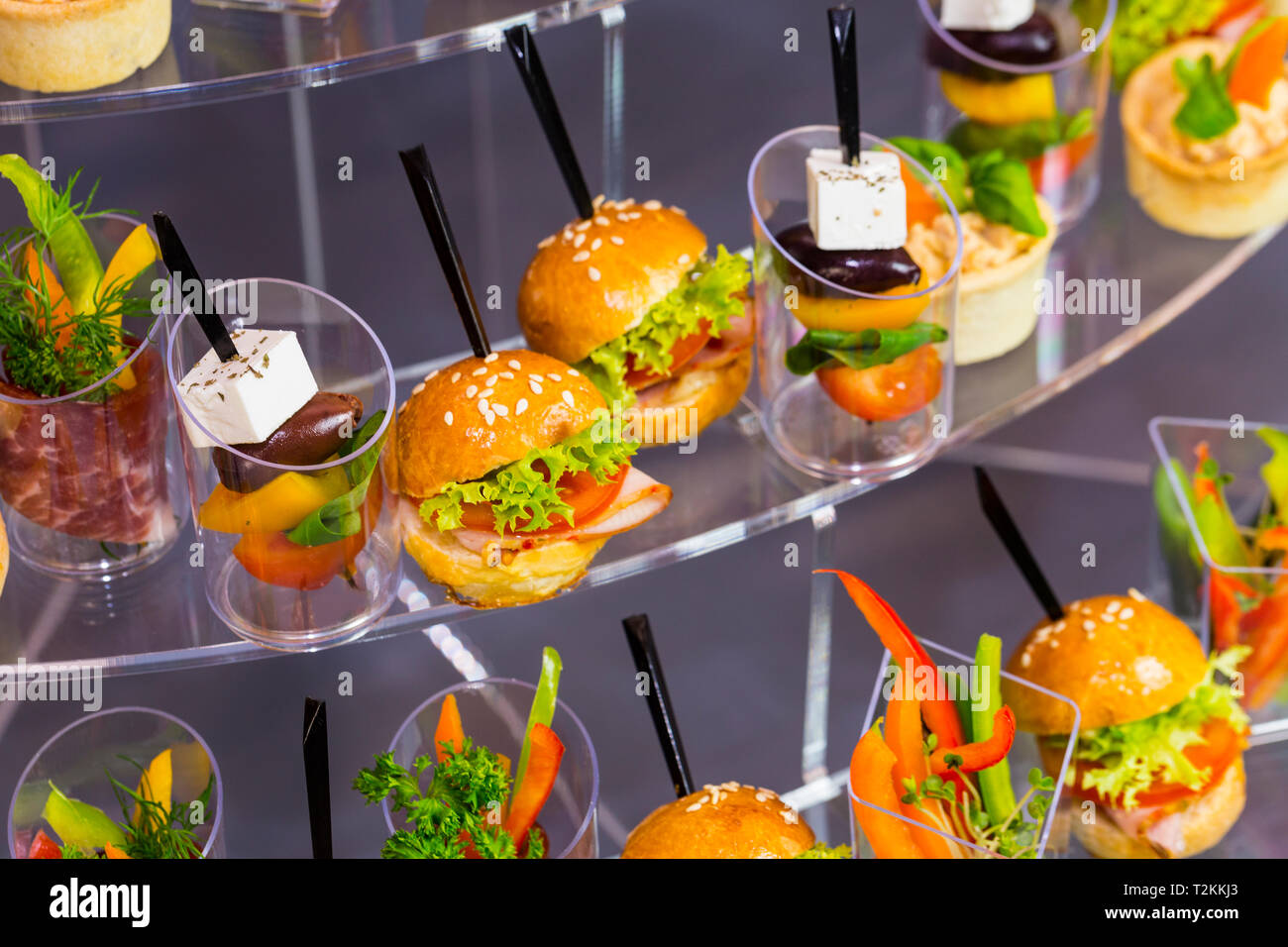 Mini canapes in plastic cups on a dark background of granite stone ...