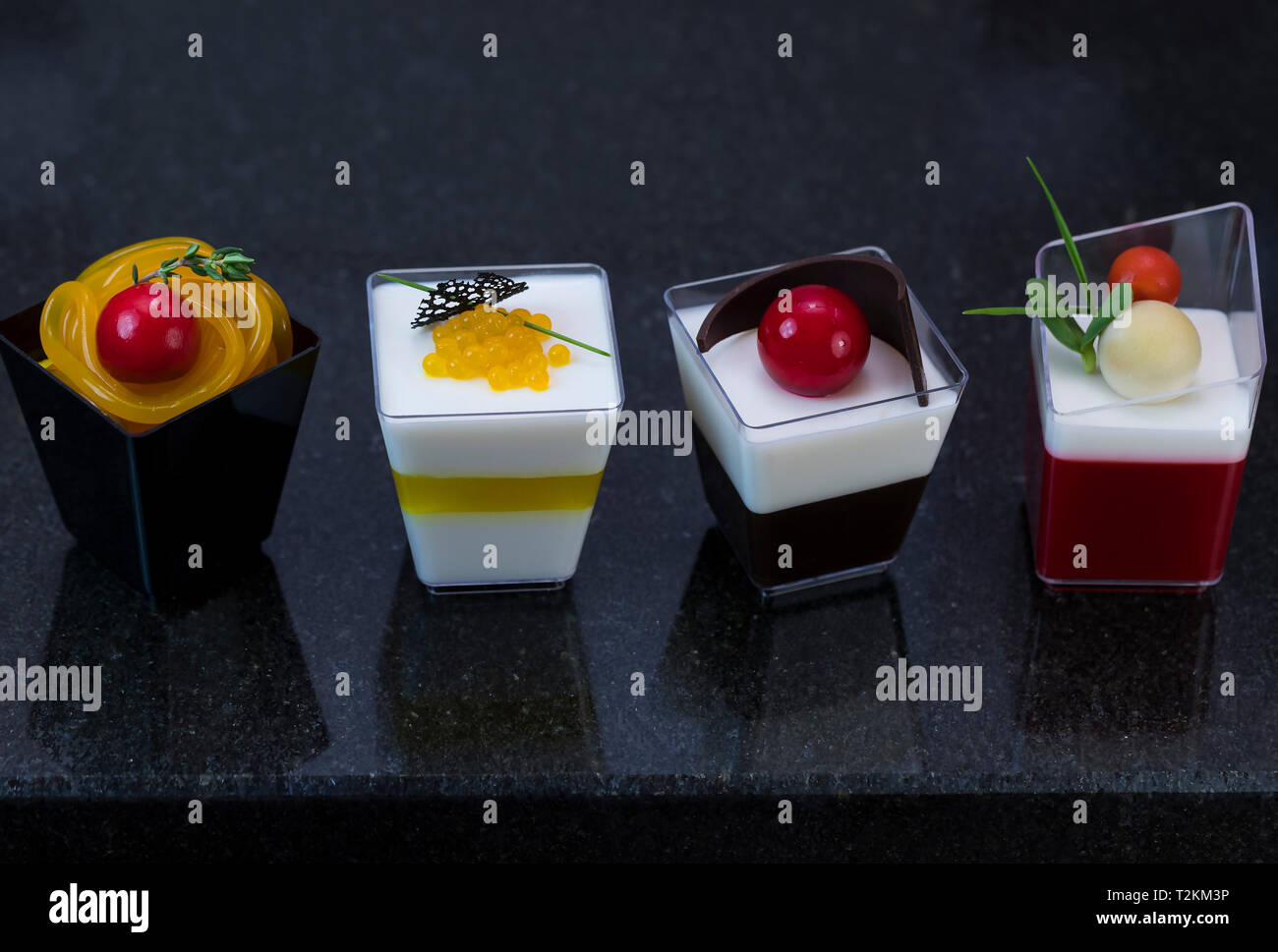 Mini canapes in plastic cups on a dark background of granite stone ...