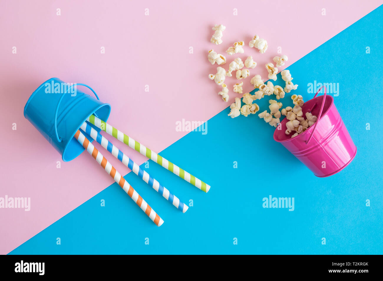 Flat lay of small metal buckets with popcorn and drinking straws on ...