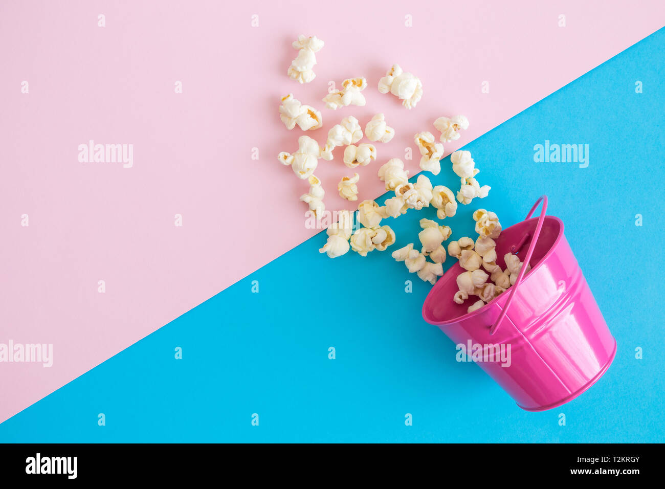 Flat lay of small metal bucket with spilled popcorn on pastel ...