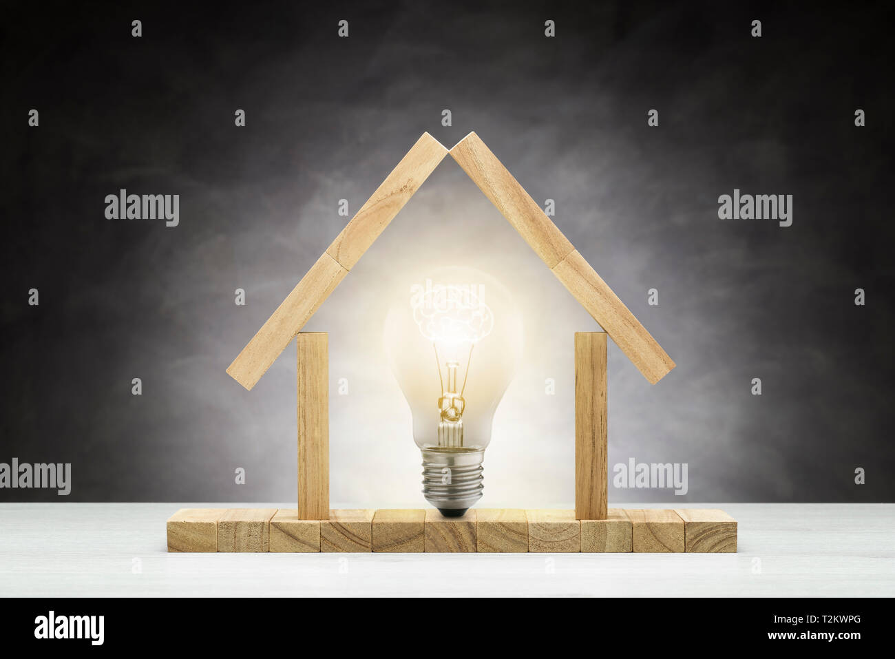 Concept of idea. Light bulb lit inside a small wooden house Stock Photo ...