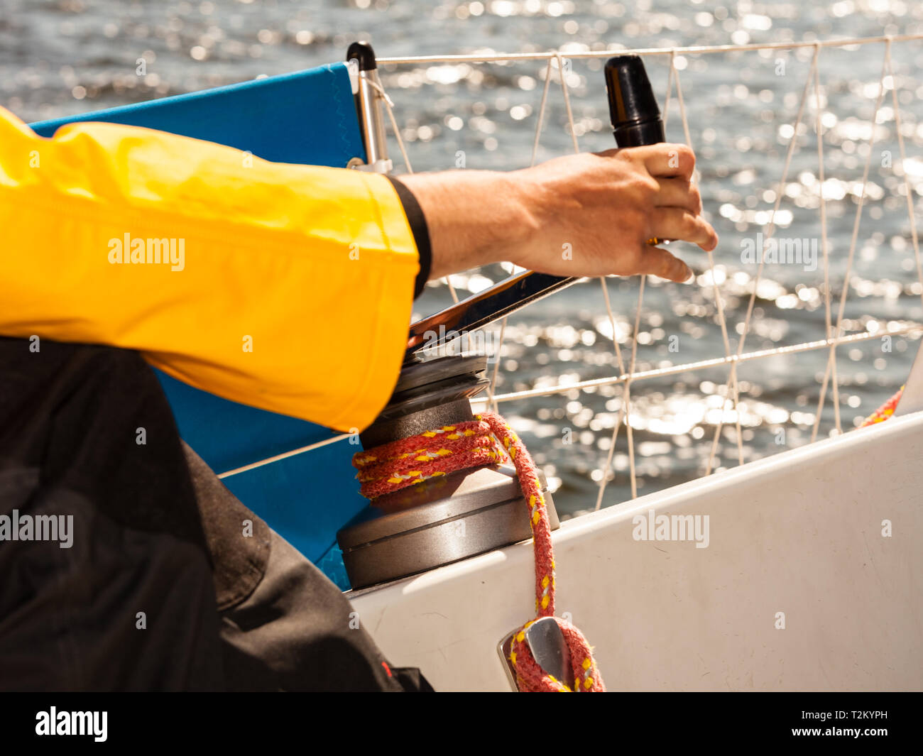 Male hand on winch capstan with rope on sailing boat. Yachting yacht in ...