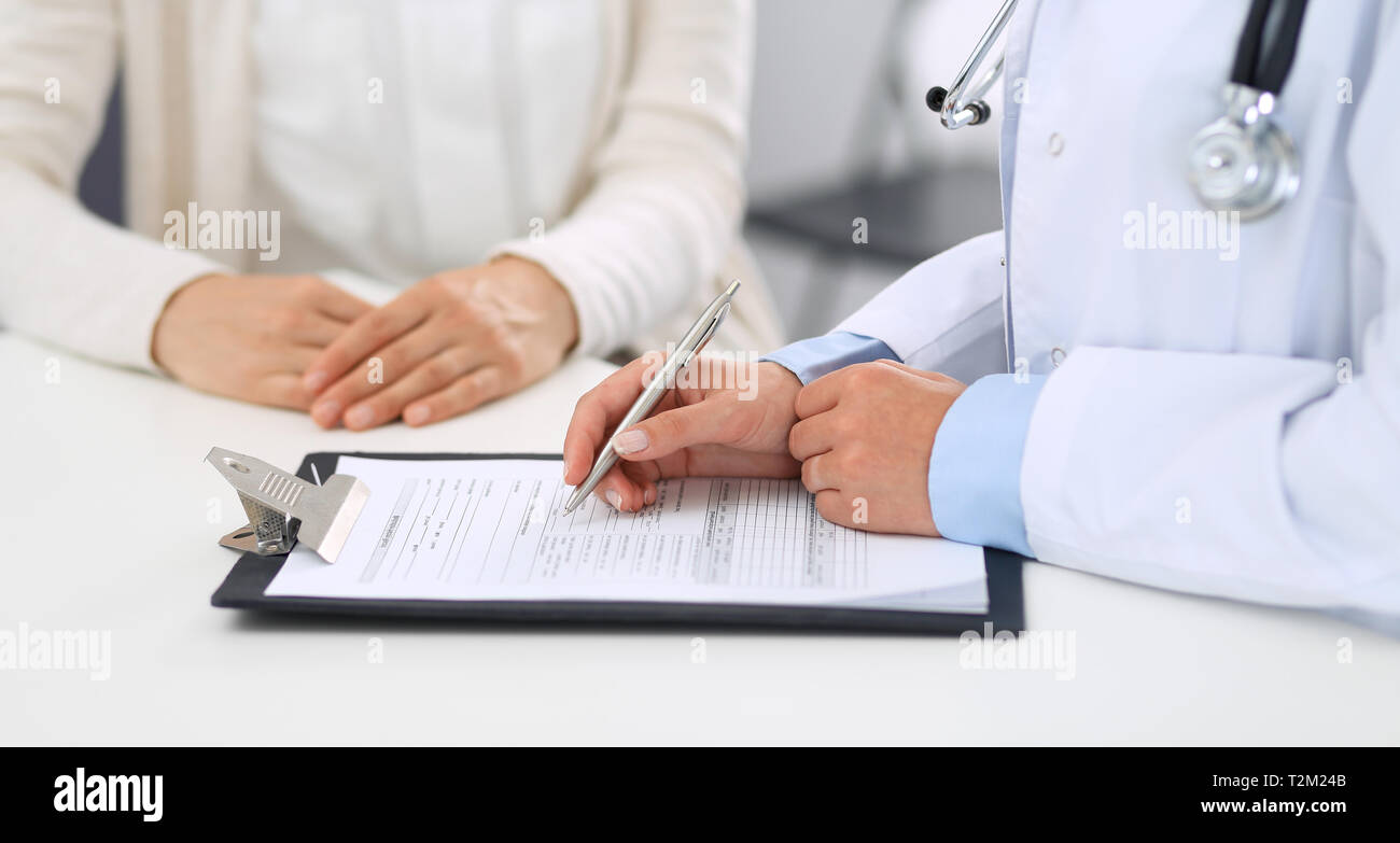 Unknown woman doctor and female patient discussing something while ...