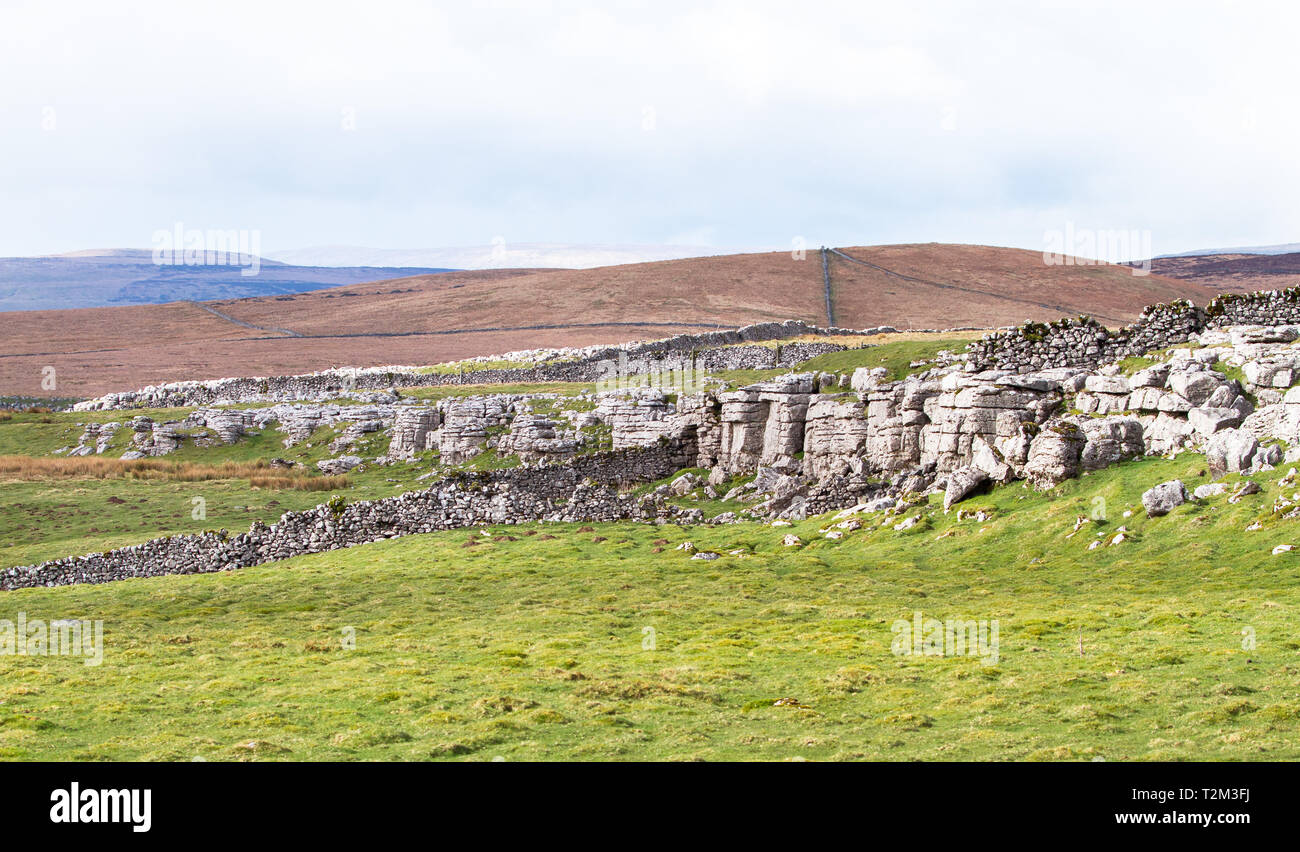 Natural rock cliffs sit next to manmade rock walls in a grassy and ...
