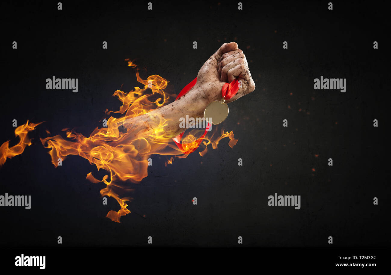 Man arm holding burning medal on dark background Stock Photo - Alamy