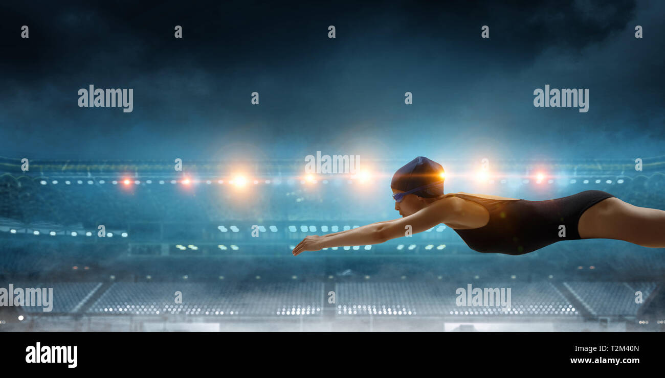 Swimmer standing on diving board ready to jump into swimming pool ...