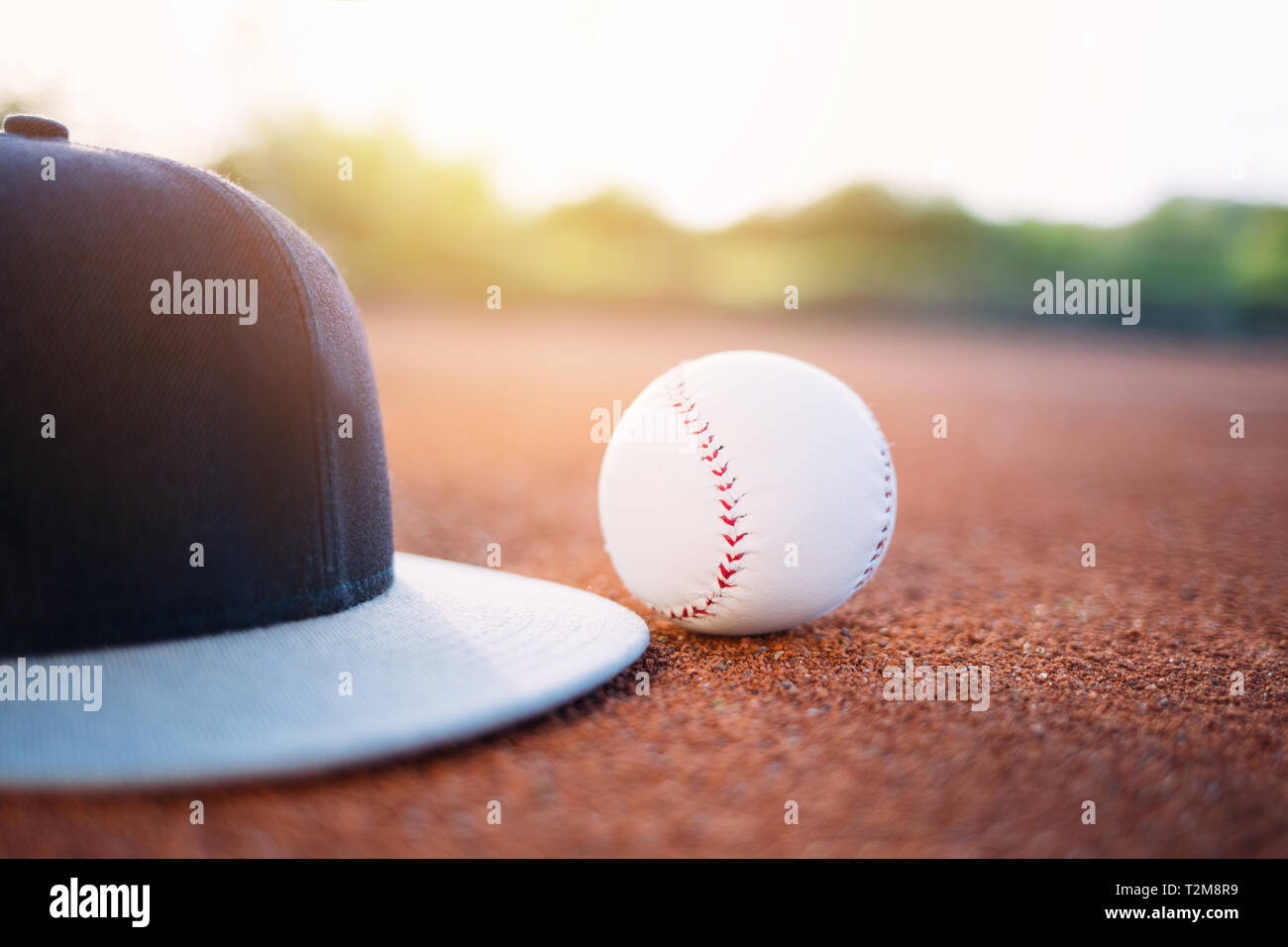Baseball cap and baseball ball on baseball field Stock Photo - Alamy