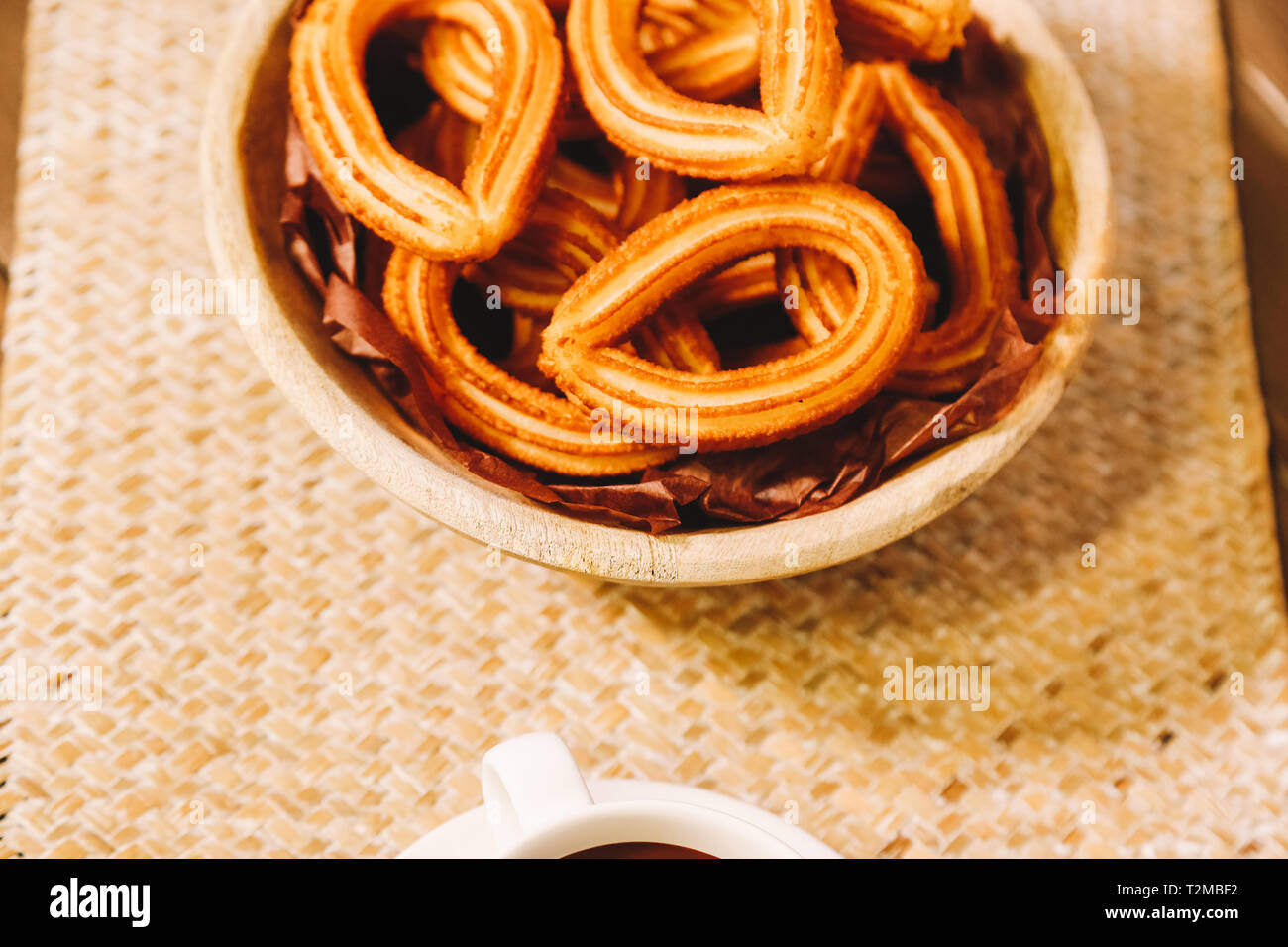spanish fritters served on a wooden table with a cup of hot chocolate ...