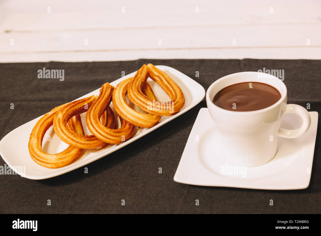 spanish fritters served on a wooden table with a gray tablecloth and a ...