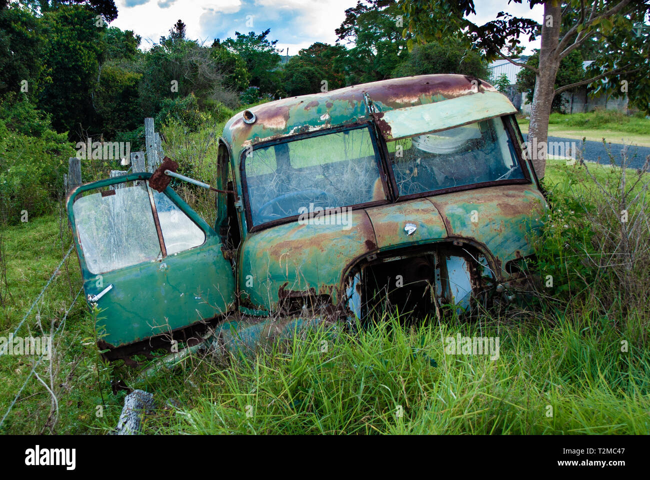 A rusty, destroyed vintage car dumped at the side of a road Stock Photo ...