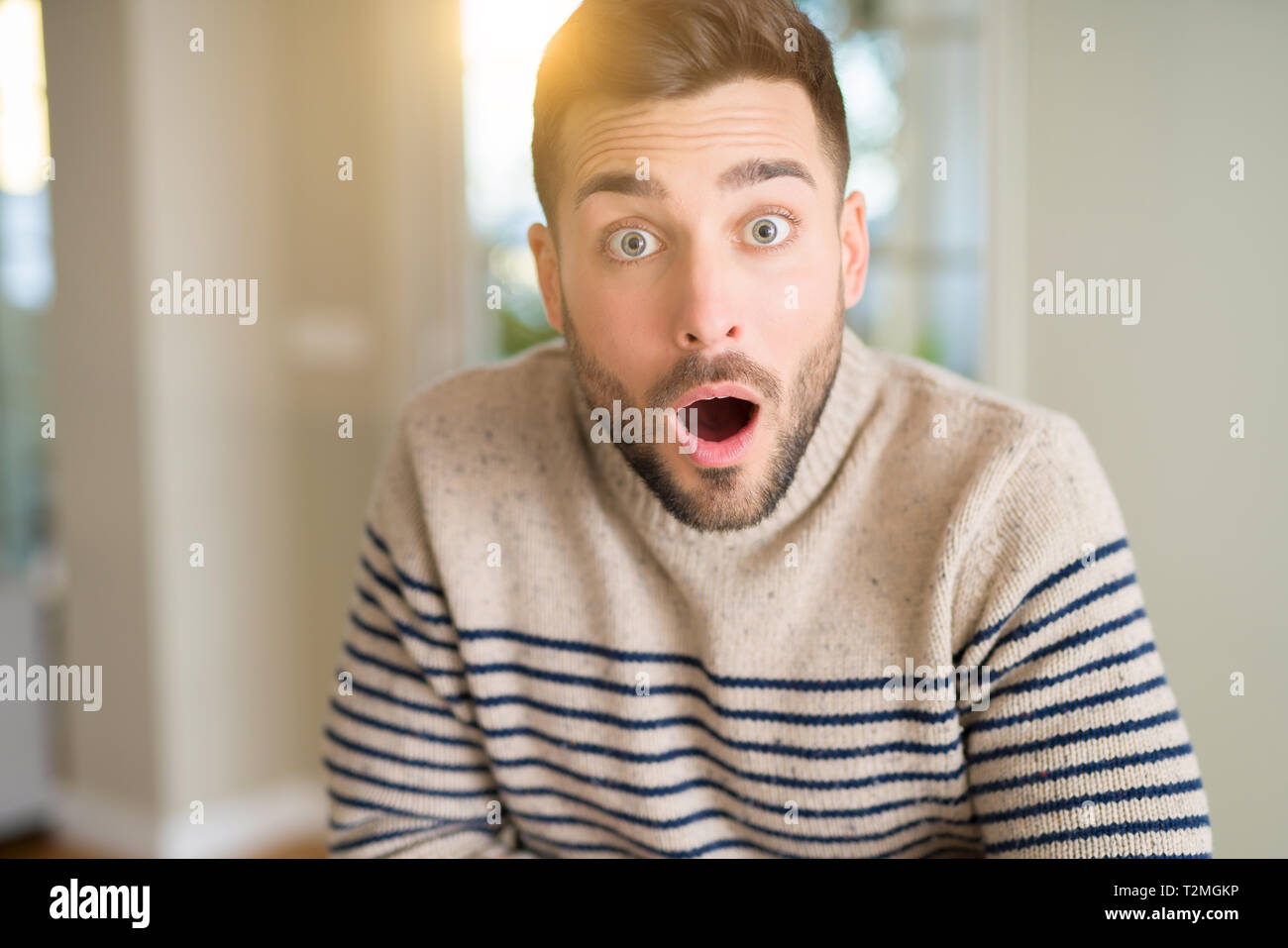 Young handsome man at home scared in shock with a surprise face, afraid ...