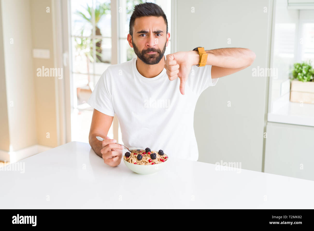 Handsome hispanic man eating healthy breakfast in the morning at home ...