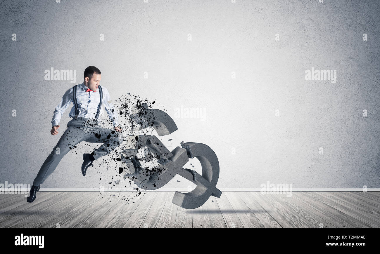 Young furious businessman jumping and crashing with kick stone dollar ...
