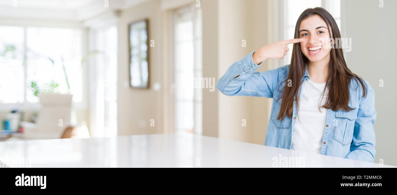 Wide angle picture of beautiful young woman sitting on white table at ...