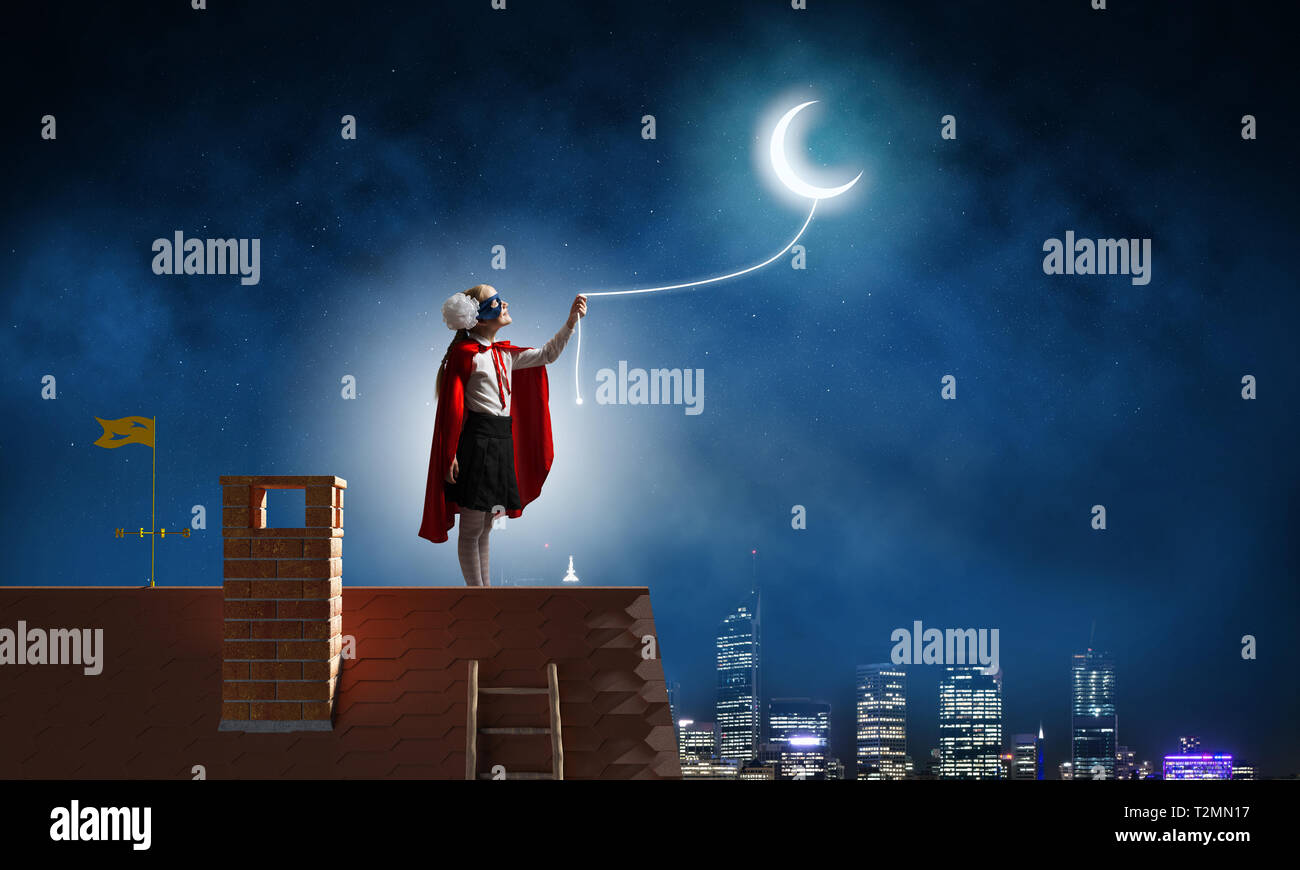 Kid girl in mask and cape catching moon in sky Stock Photo - Alamy