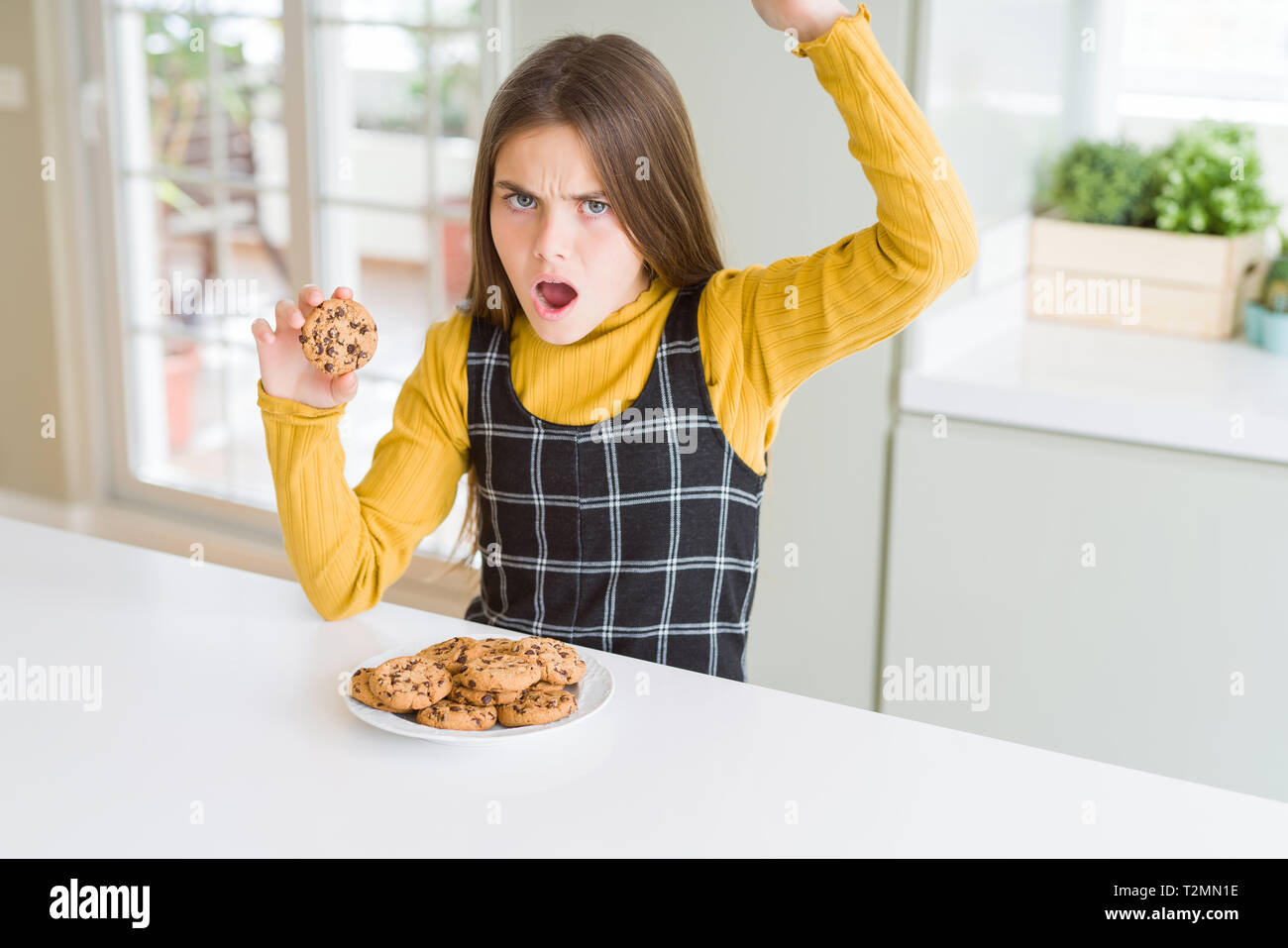 Beautiful young girl kid eating chocolate chips cookies annoyed and ...